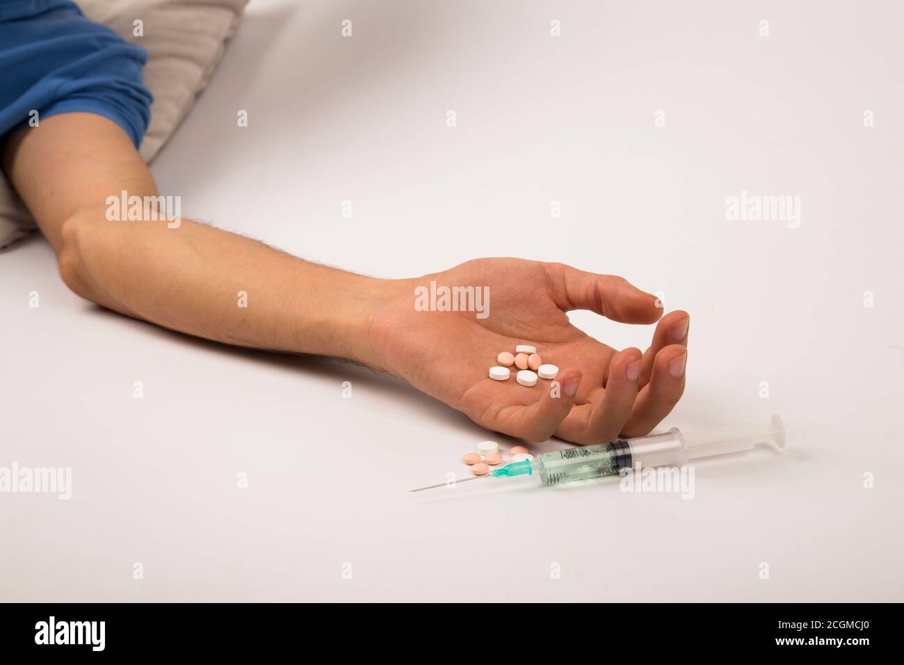 Drug addiction concept - passive hand with coat, pills and injection ...