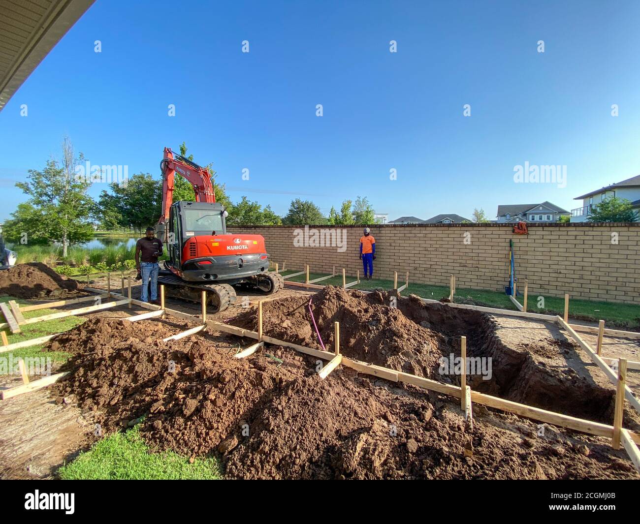 Orlando, FL/USA - 5/21/20: A backhoe digging a hole for a pool behind a ...