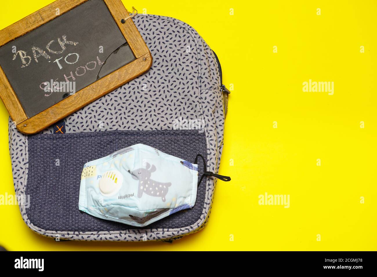 top view of blackboard with back to school message on backpack and boy ...