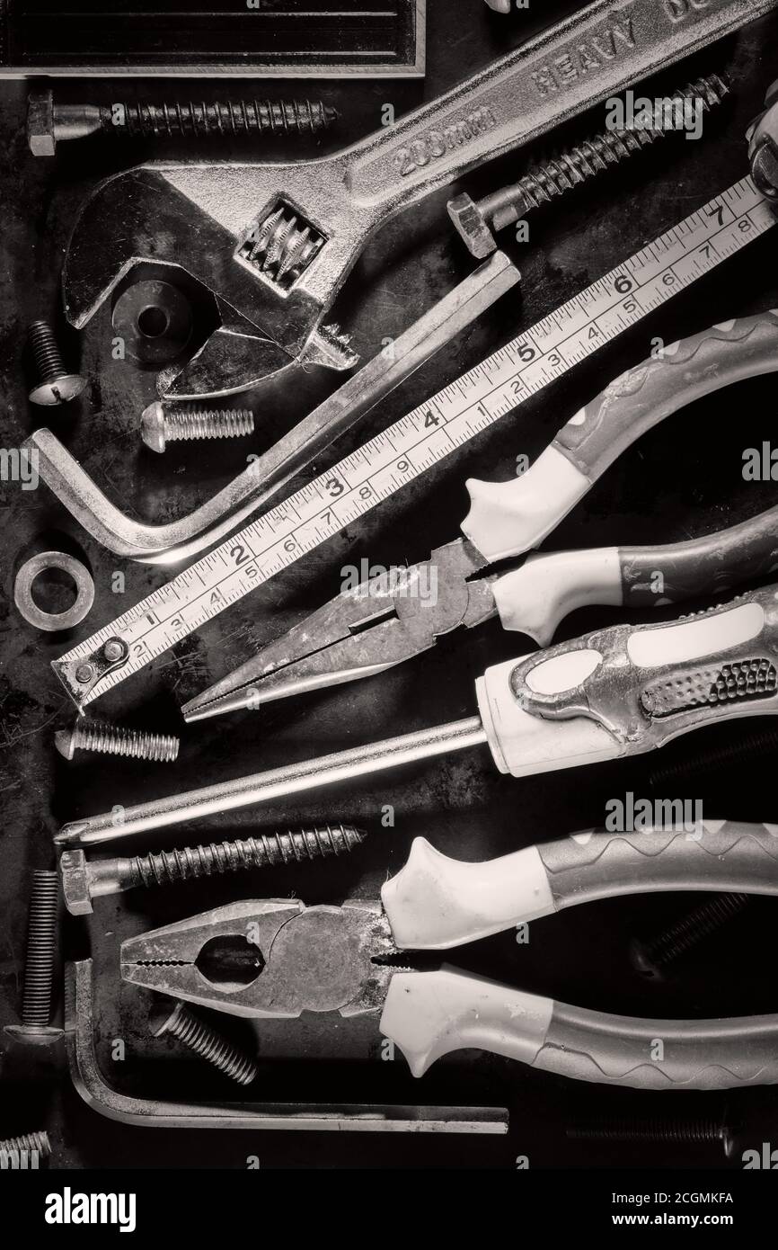 Old tools and screws on a metallic background photographed in black and ...