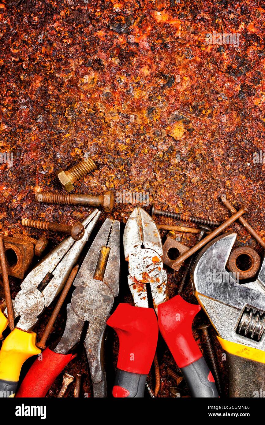 Vertical shot of a set of tools, nuts and bolts on a rusty metallic ...