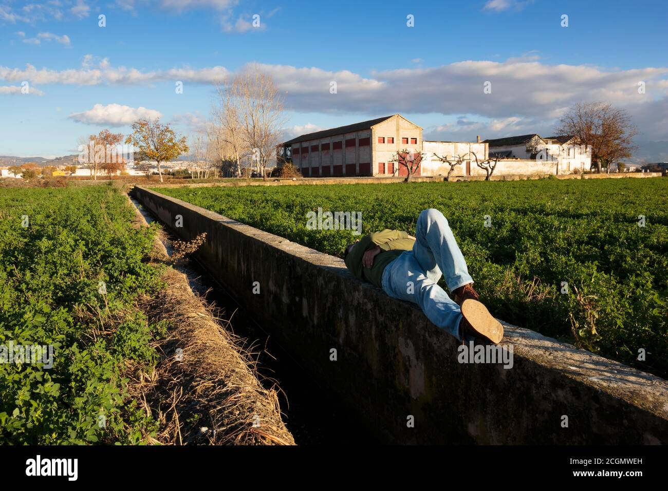 Man lying down and sleeping relaxed in a ditch wall Stock Photo - Alamy