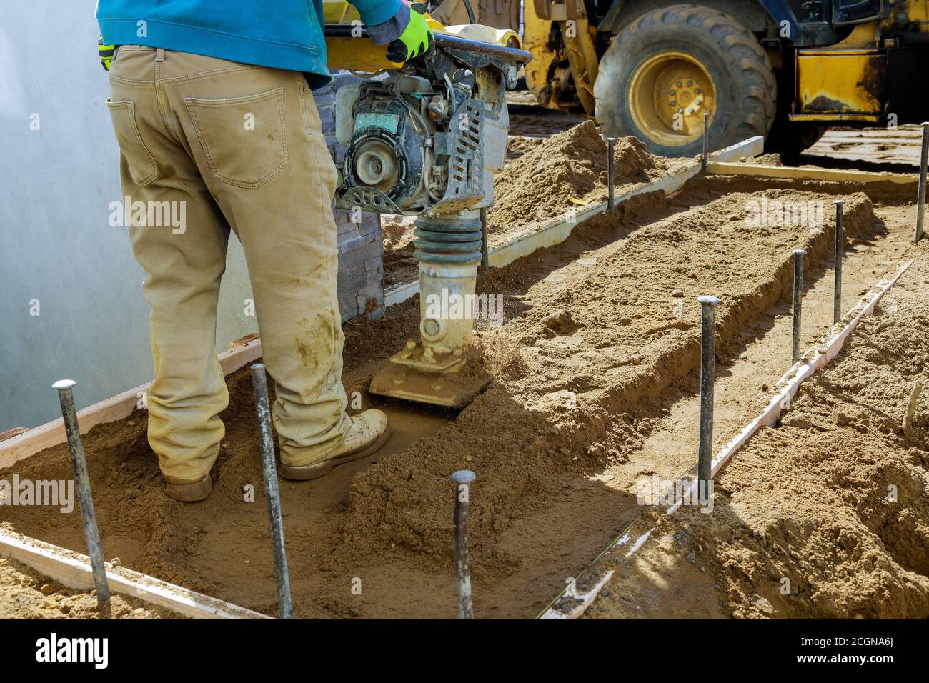 Worker compressed sand in around new sidewalk with special working tool ...