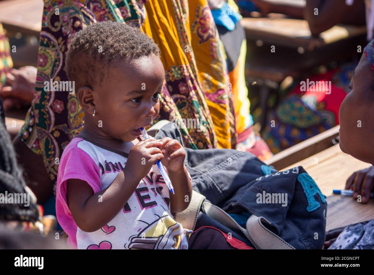 Young baby girl holding a pen opposite her mother Stock Photo - Alamy