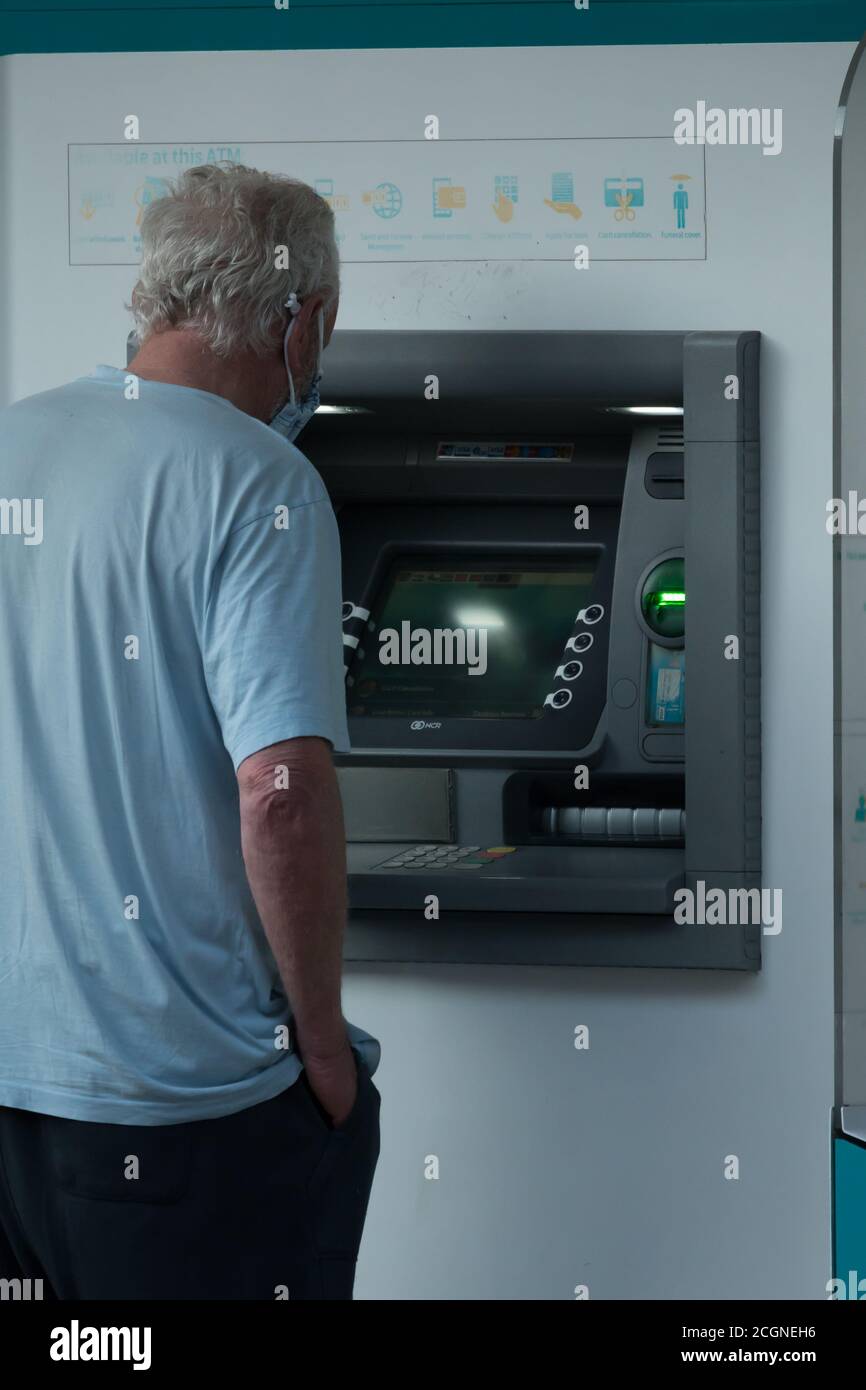 man wearing face mask standing at an ATM withdrawing money in Cape Town ...