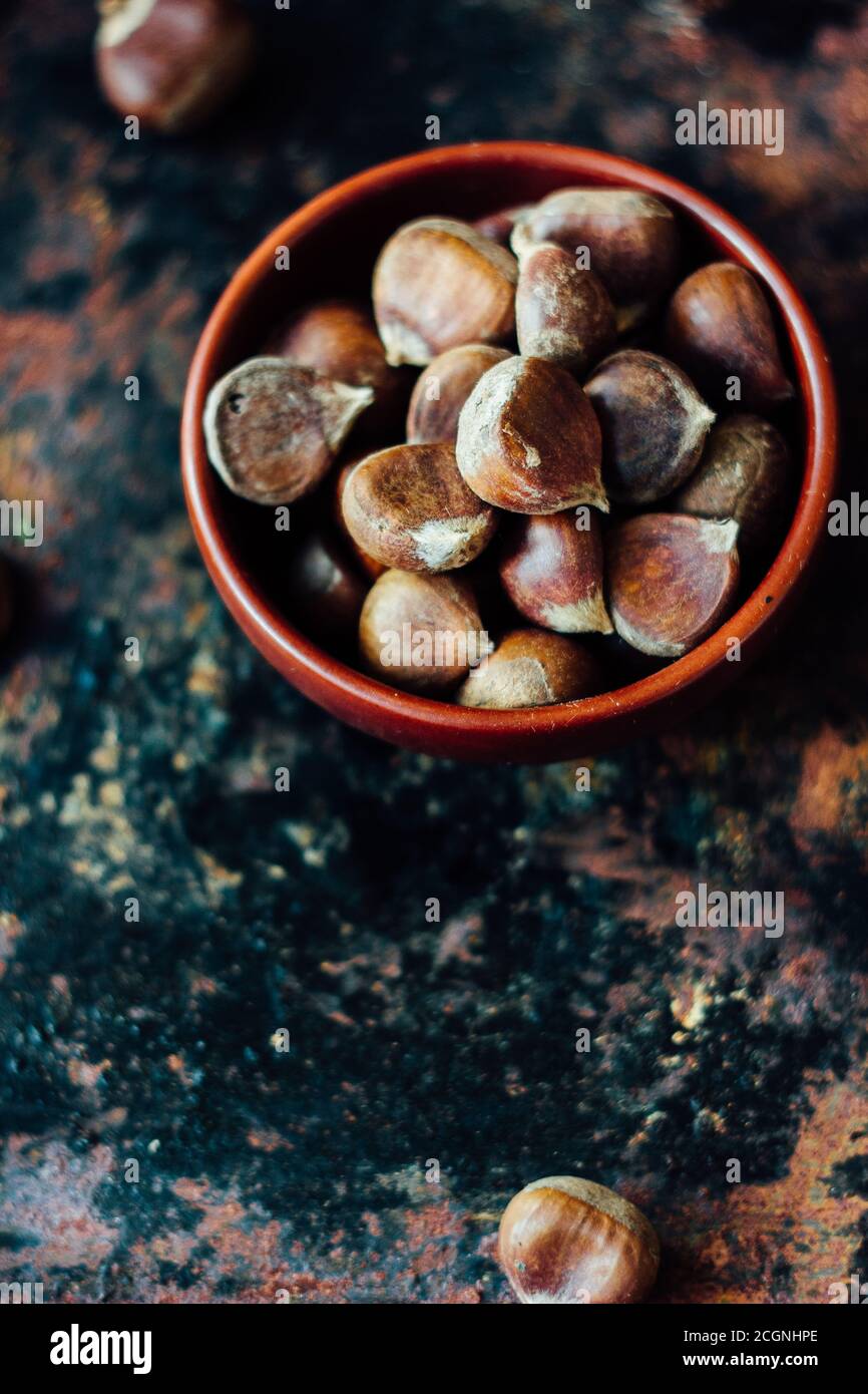 Raw chestnuts in ceramic bowl on black rustic surface Stock Photo - Alamy
