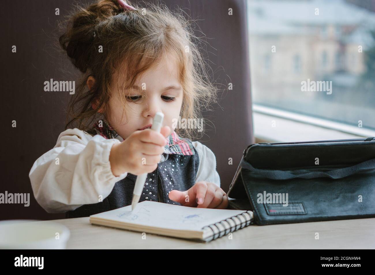 Little kid girl writing or drawing with pen in scetch book Stock Photo ...
