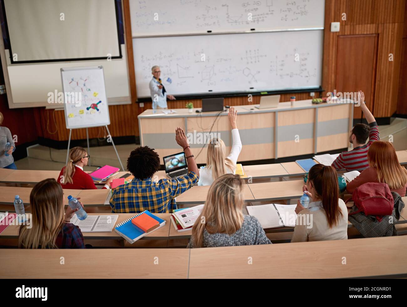 Female professor questioning students at a lecture in amphitheater ...