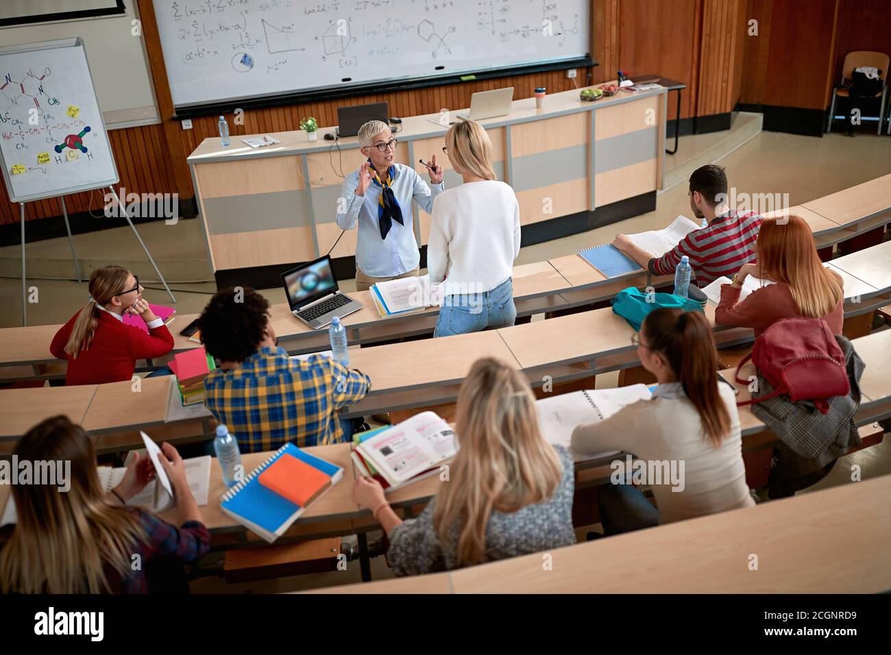 Female professor questioning the student at a lecture in amphitheater ...