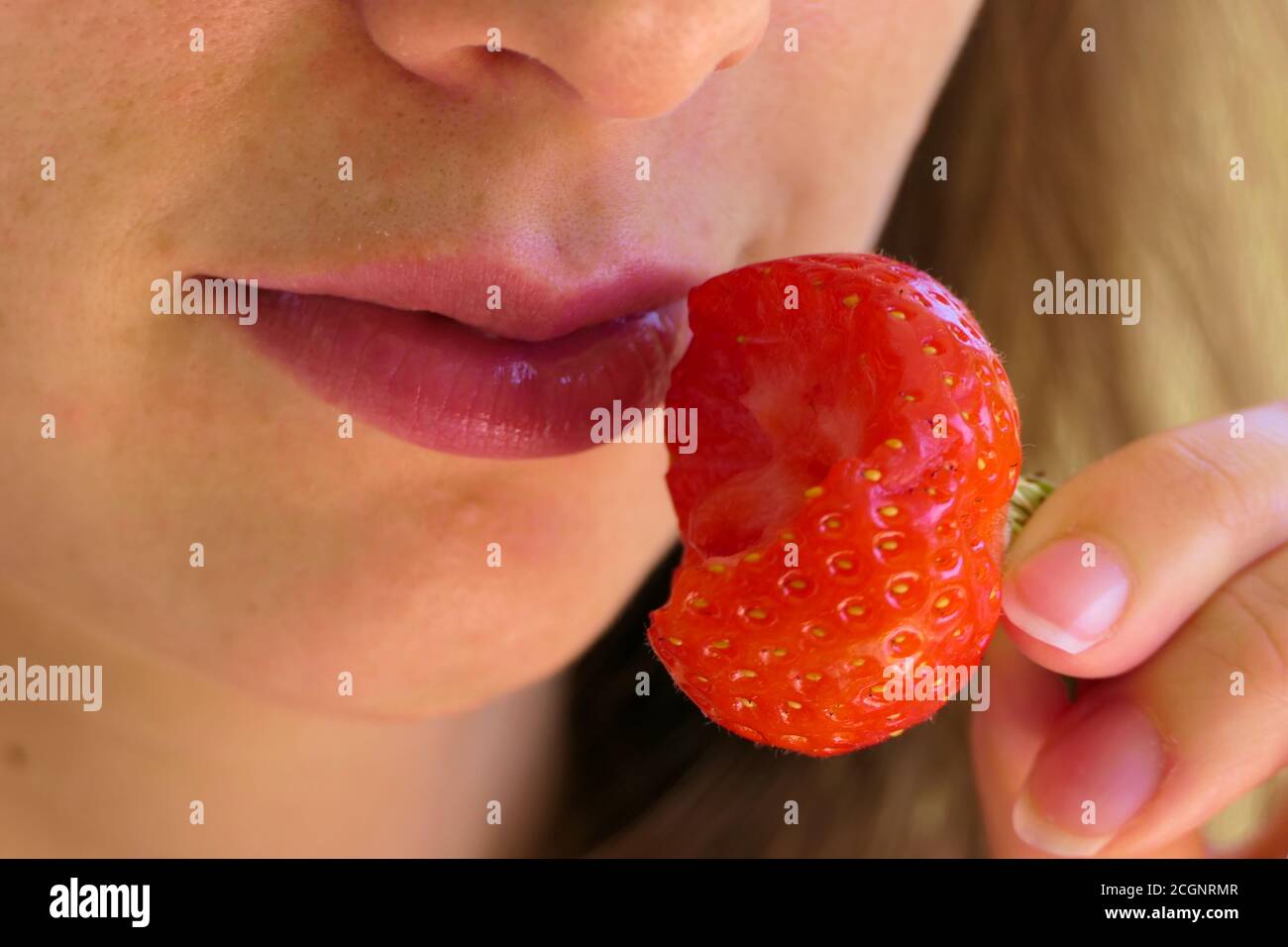 Red lips and red berry: young woman eating a strawberry Stock Photo - Alamy