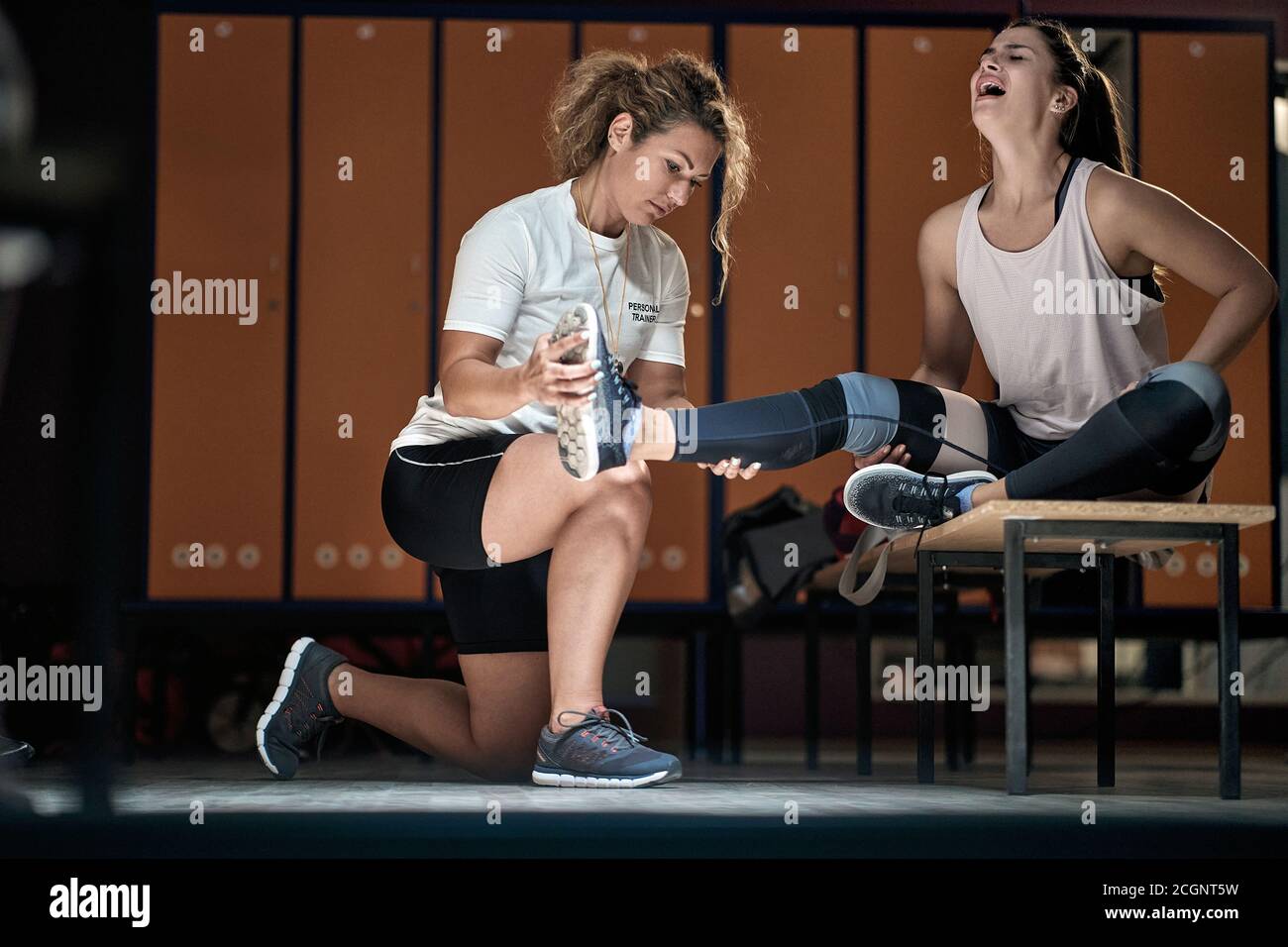 Personal female trainer helping her student in a locker room with the ...