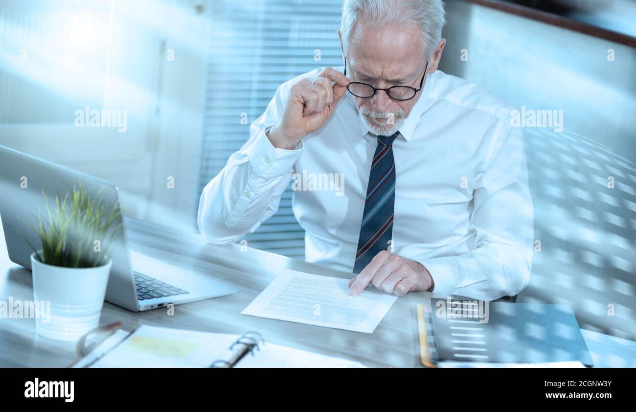 Senior businessman checking document in office; light effect Stock ...