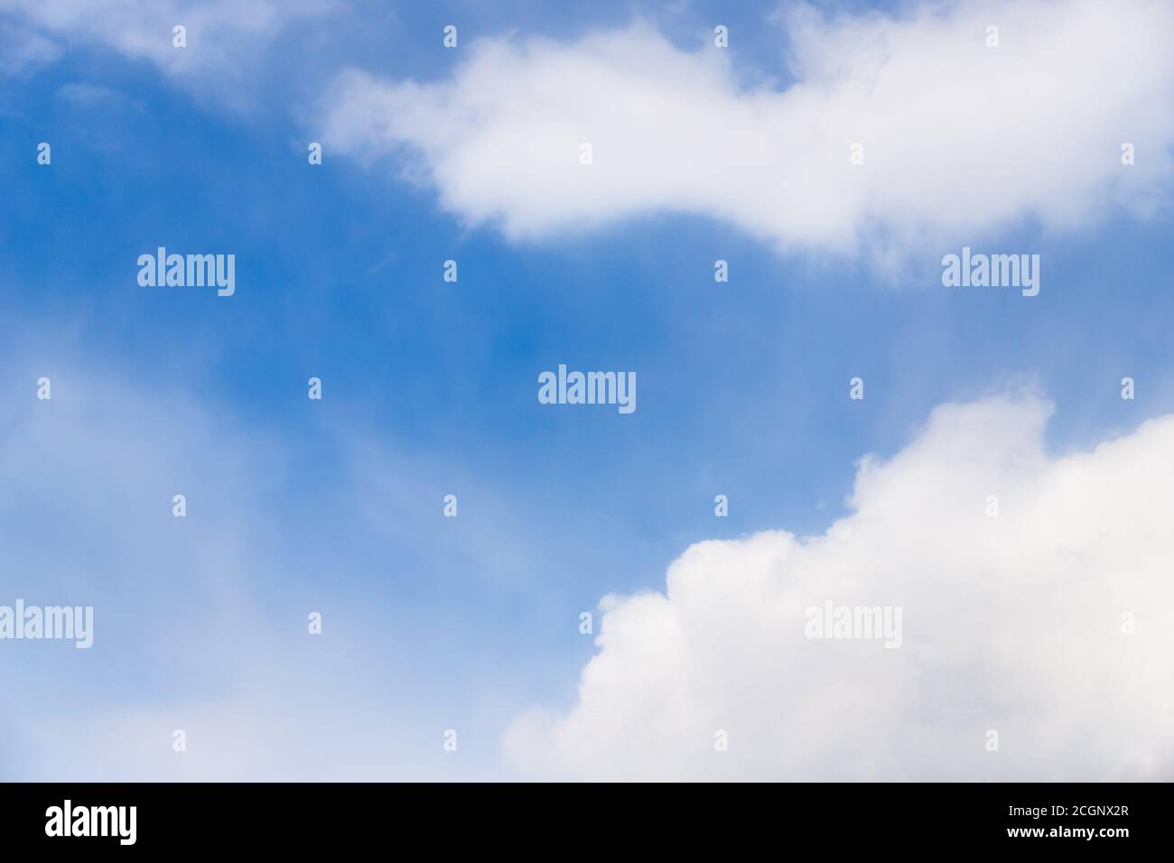 Two white fluffy clouds on a light blue sky background Stock Photo - Alamy