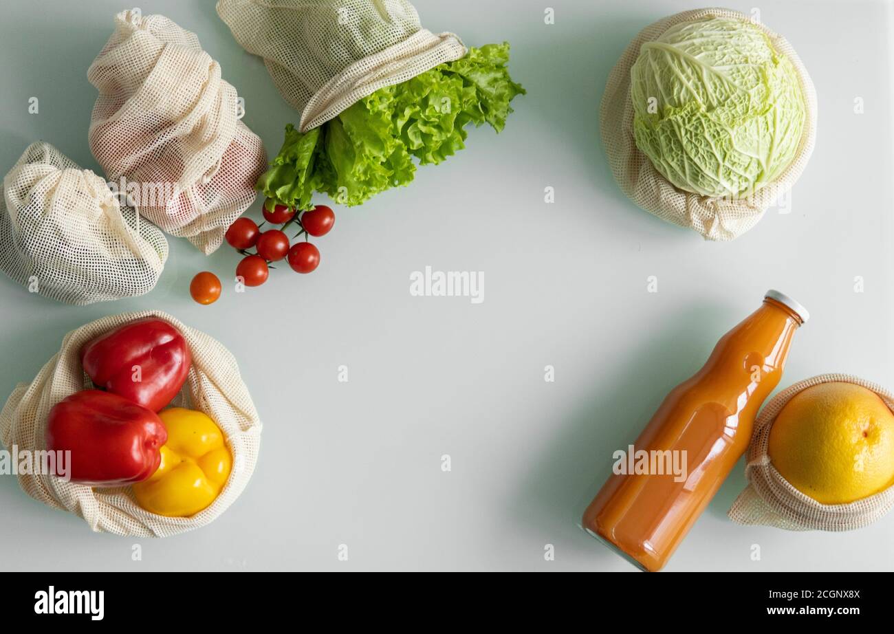 Vegetables, fruits in reusable eco cotton bags and orange juice in a ...