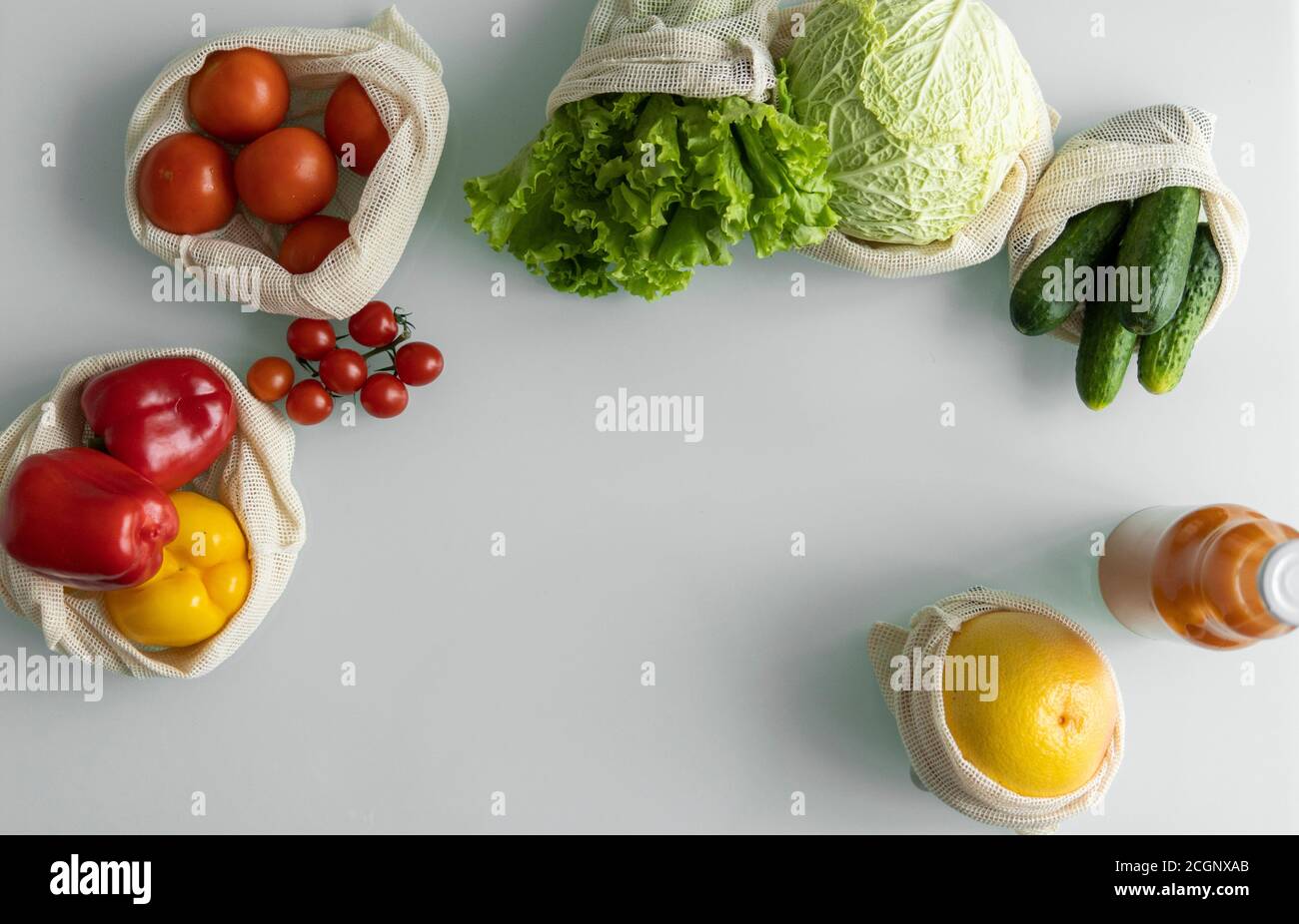 Vegetables, fruits in reusable eco cotton bags and orange juice in a ...