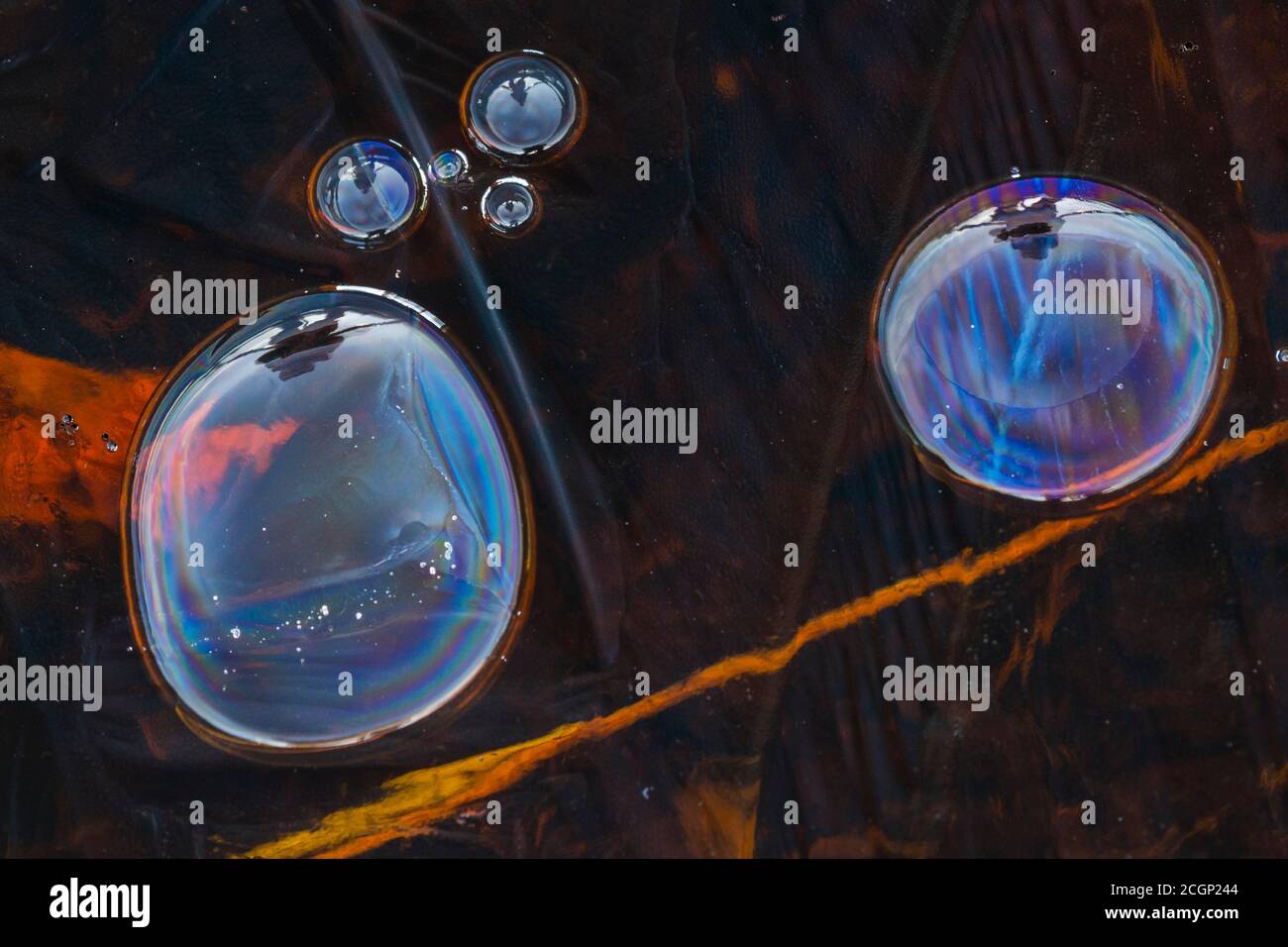 Coloured shimmering air bubbles under layer of ice on lake hi-res stock ...