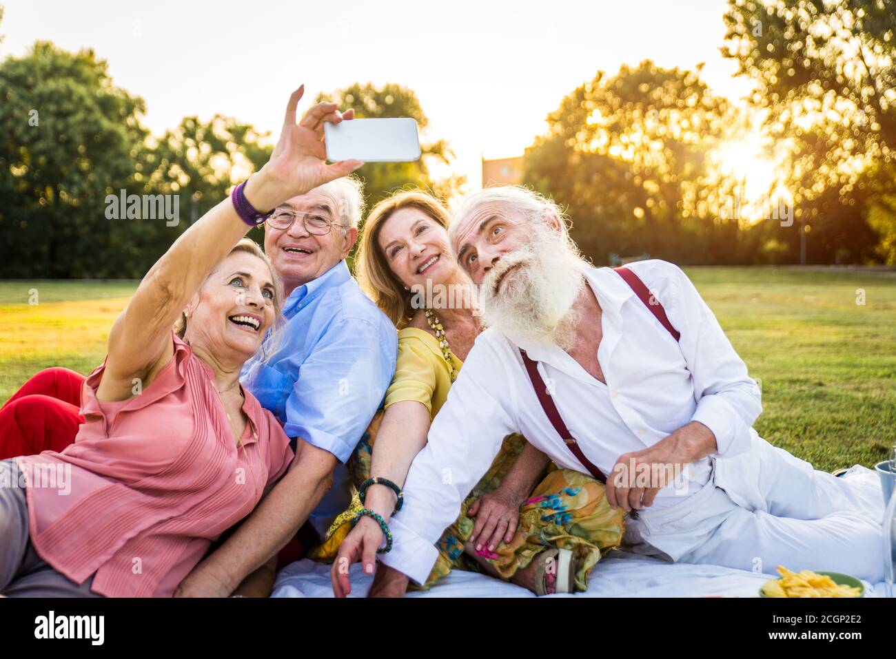 Group of youthful seniors having fun outdoors - Four pensioners bonding ...