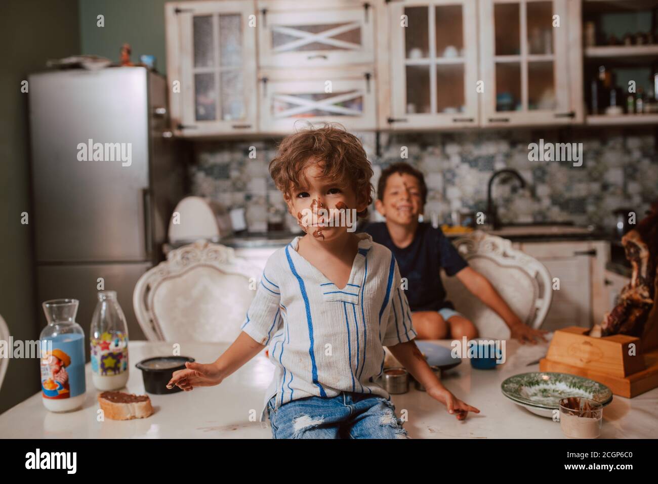 Beautiful little caucasian boy sitting on the table in the kitchen ...