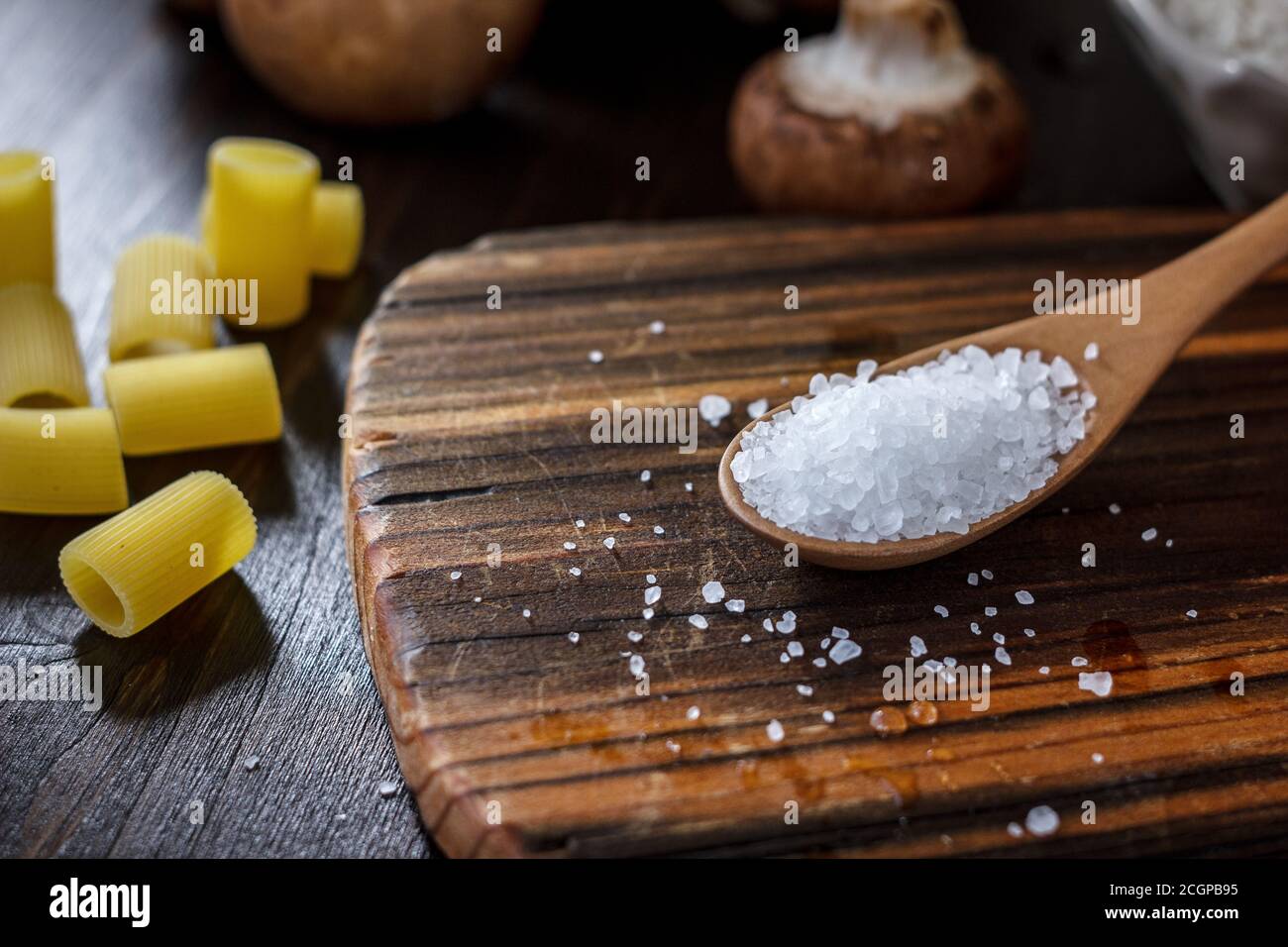 Coarse sea salt in wooden spoon over kitchen board Stock Photo - Alamy