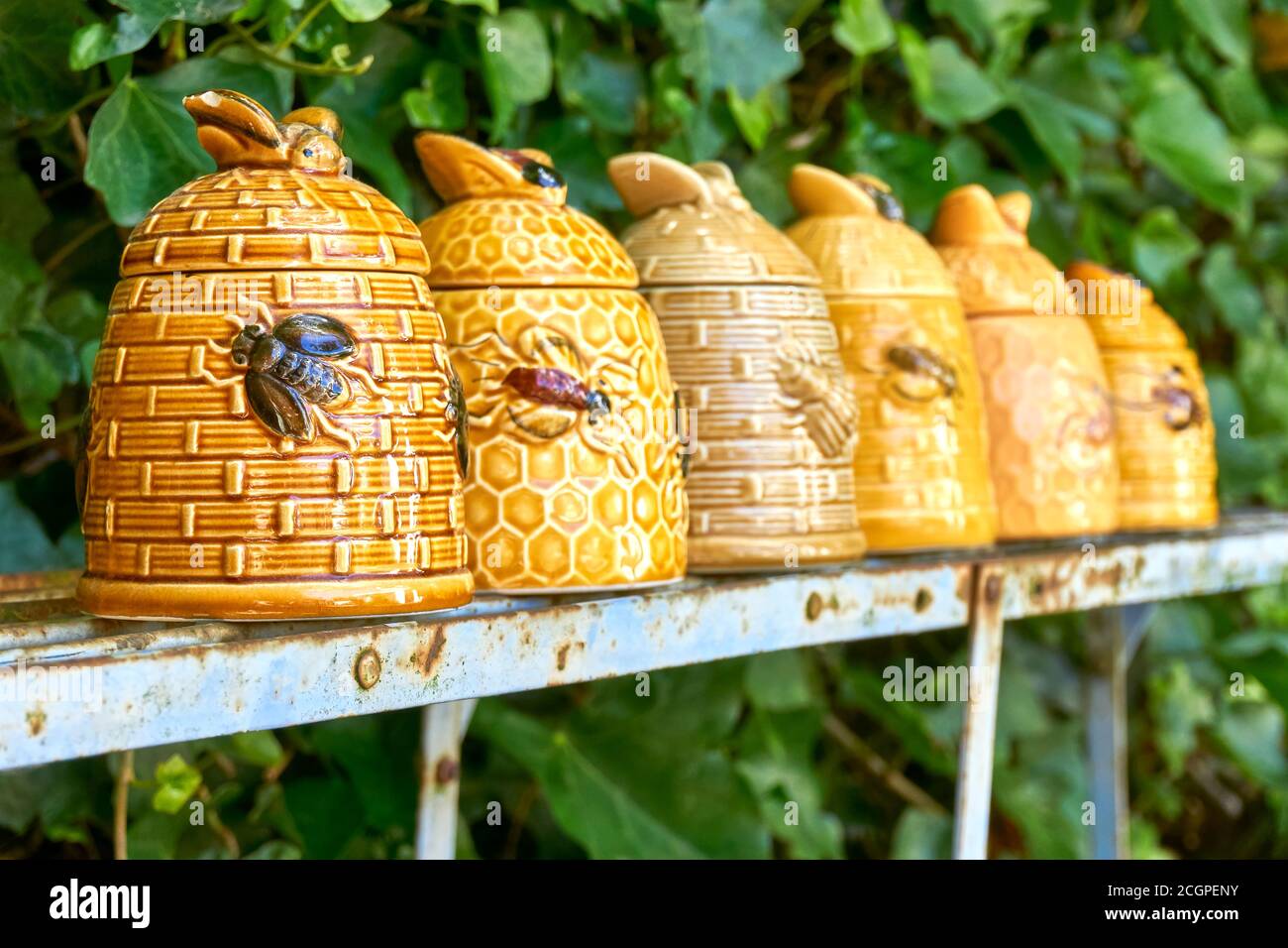 A row of vintage yellow glazed honeypots in the form of beehives in a ...