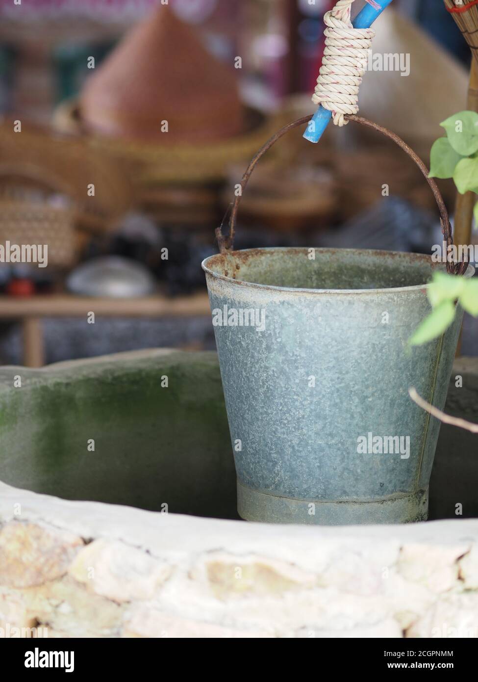 Zinc water bucket hang by hemp rope on Artesian well made of cement ...