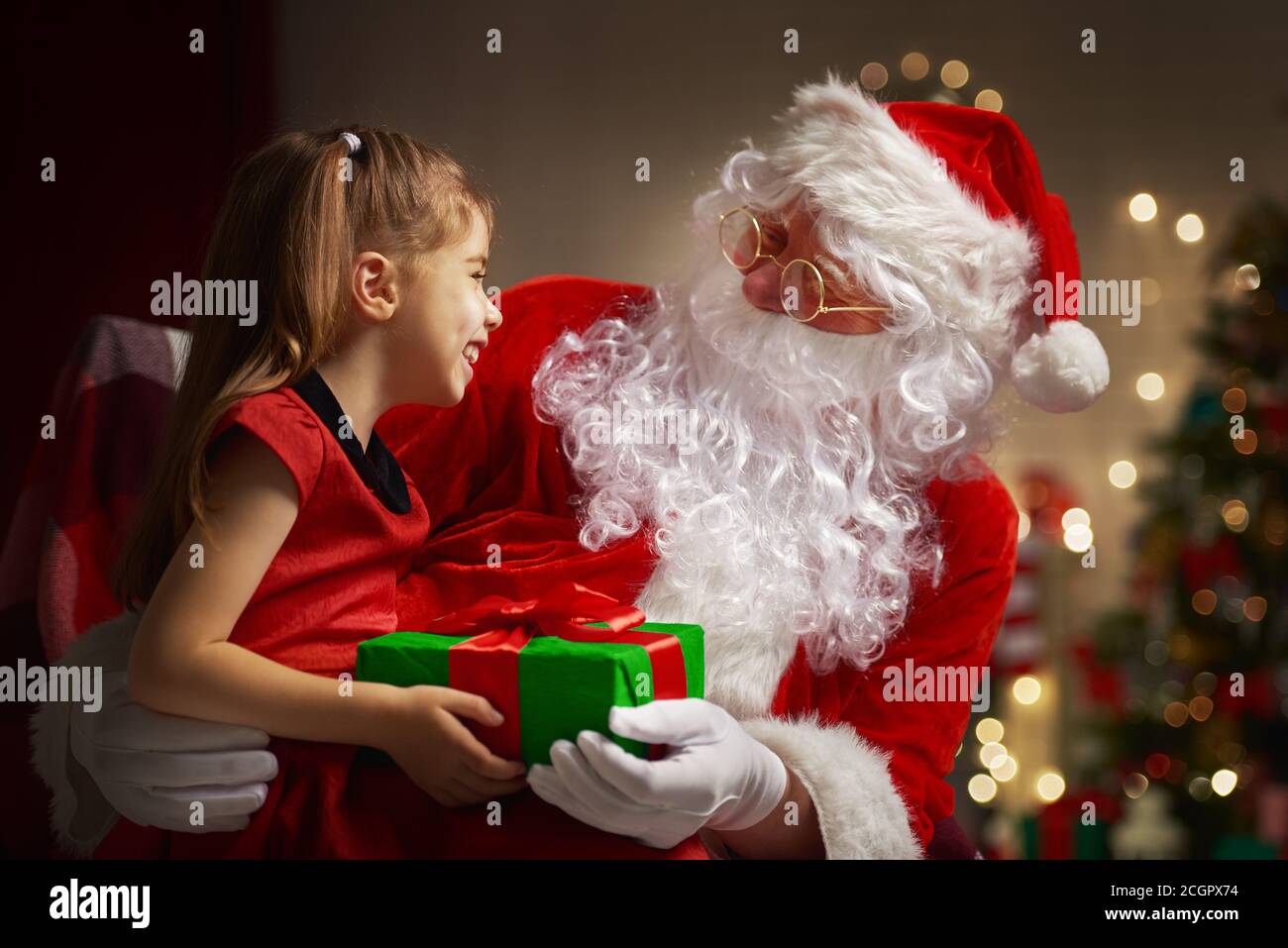 Santa Claus giving a present to a little cute girl Stock Photo - Alamy