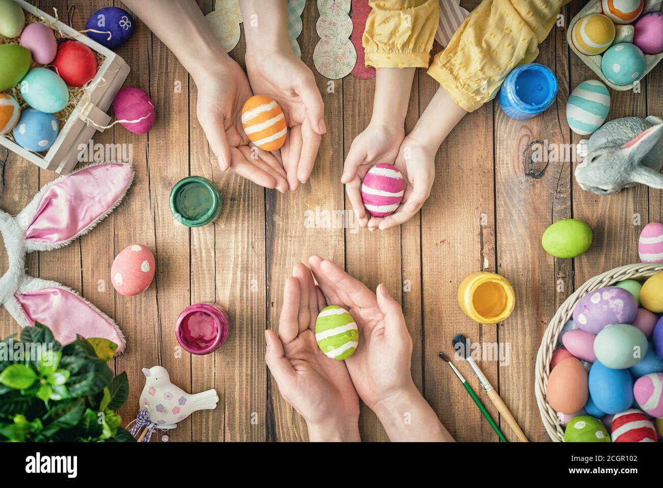 A mother, father and their child painting eggs. Happy family preparing ...