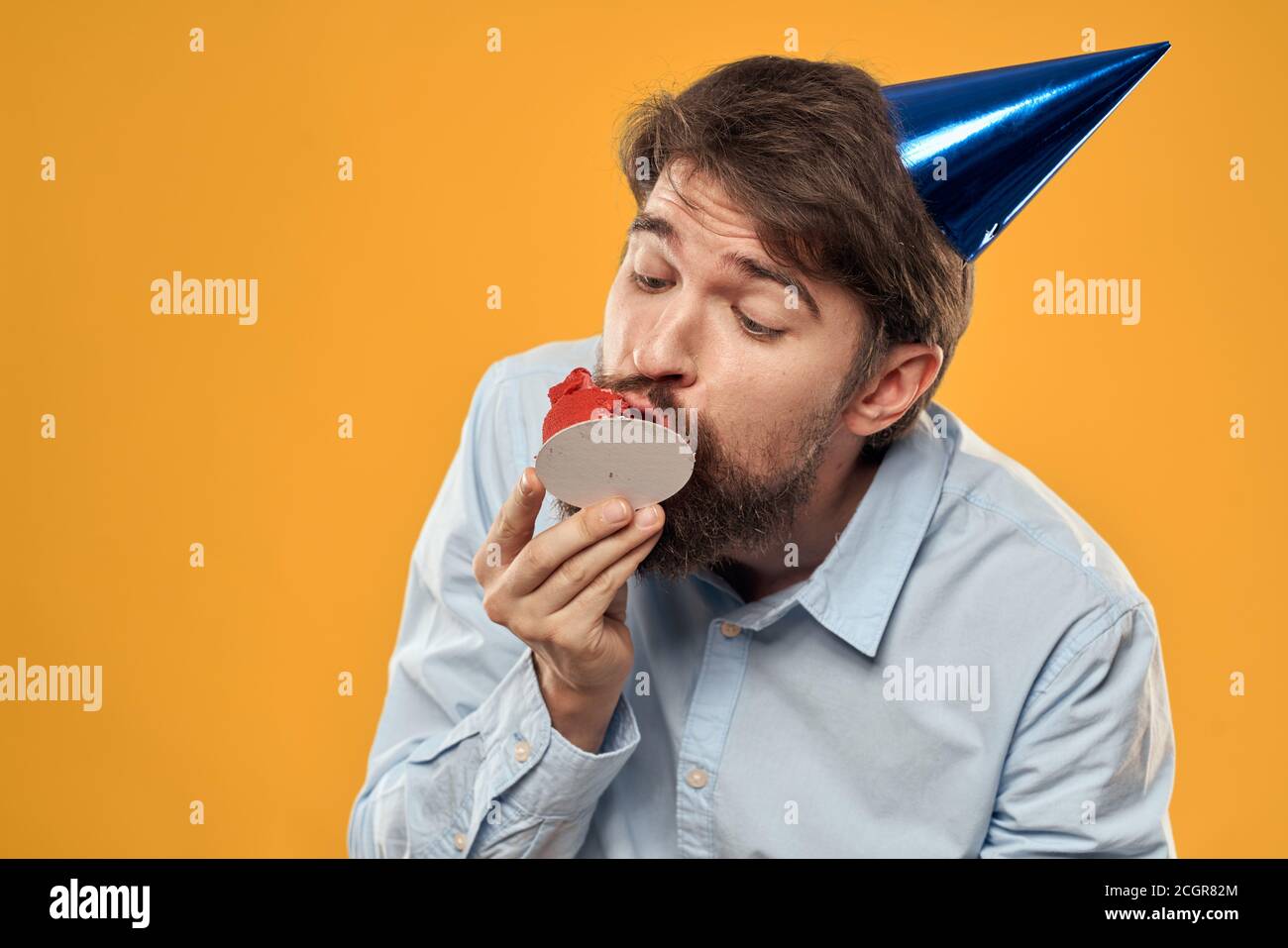 Cheerful man eating cake holiday birthday fun yellow background Stock ...