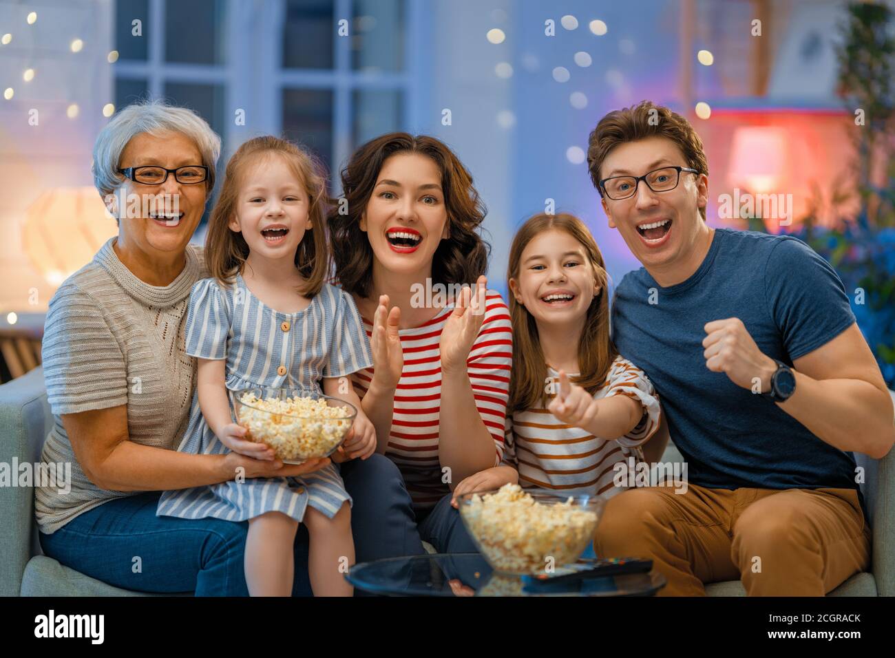 Happy family watching projector, TV, movies with popcorn in the evening ...