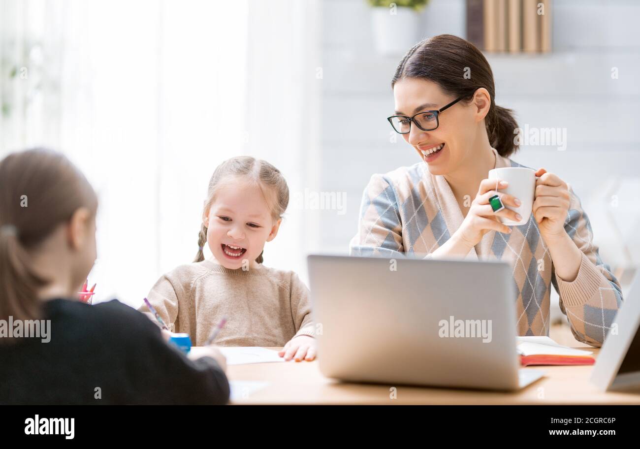 Young mother with children working on the computer. Family at home ...
