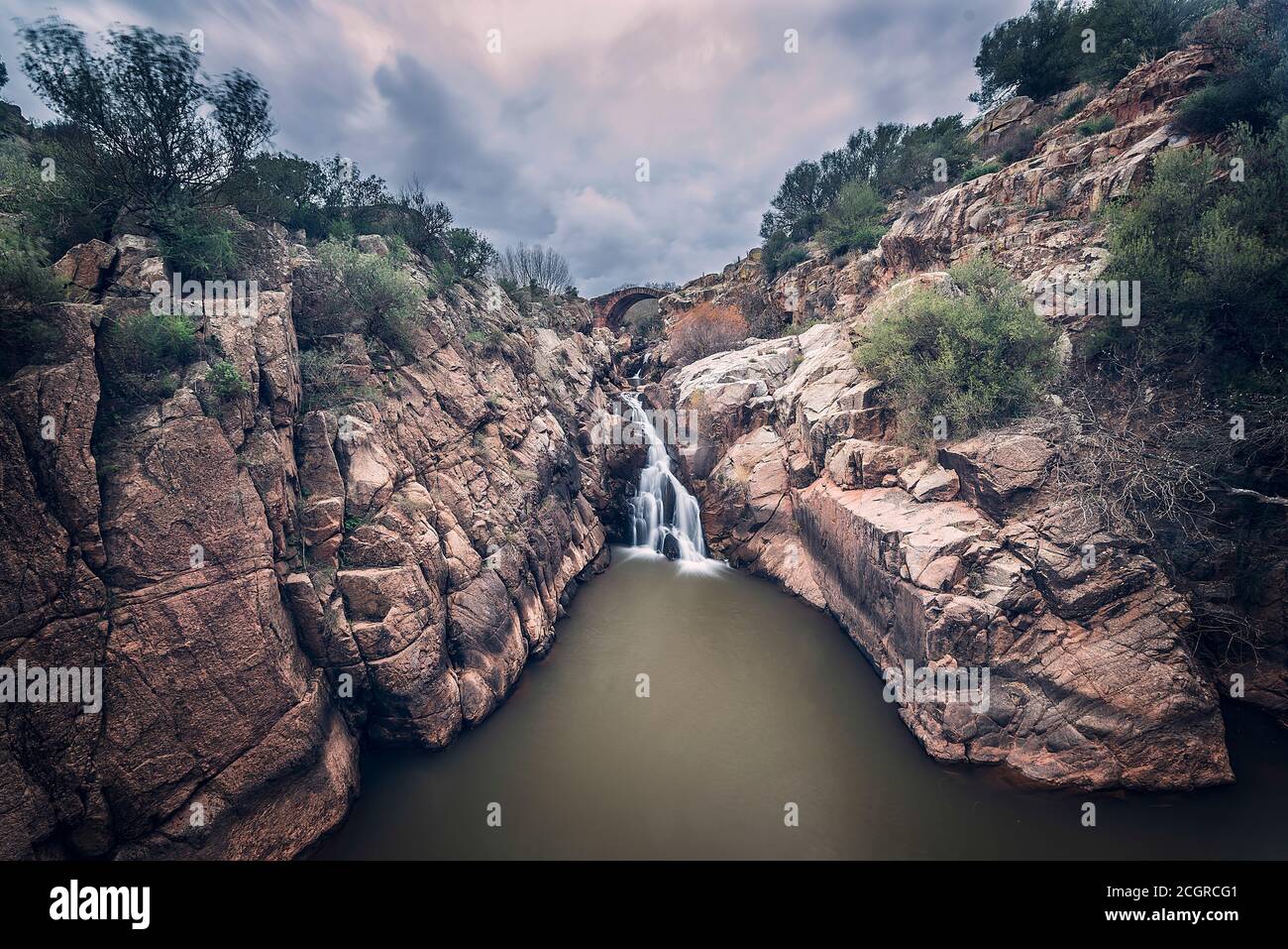 Landscape of rocks and water forming a small waterfall with trees on ...