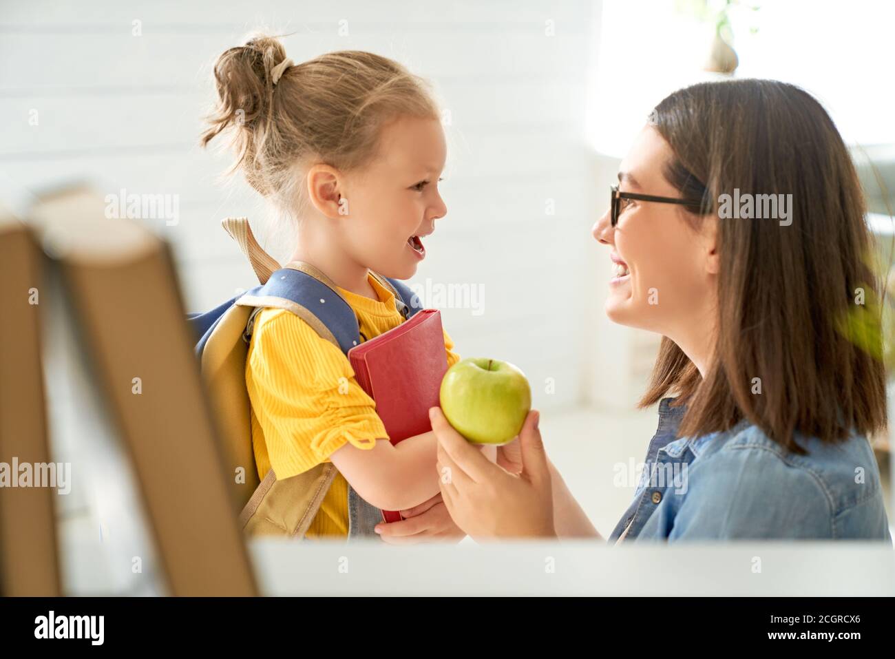 Parent and pupil of preschool. Woman and girl with backpack behind back ...