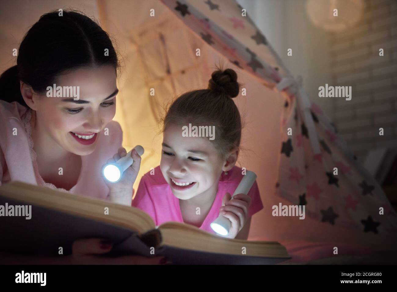 Family bedtime. Mom and child daughter are reading a book with ...