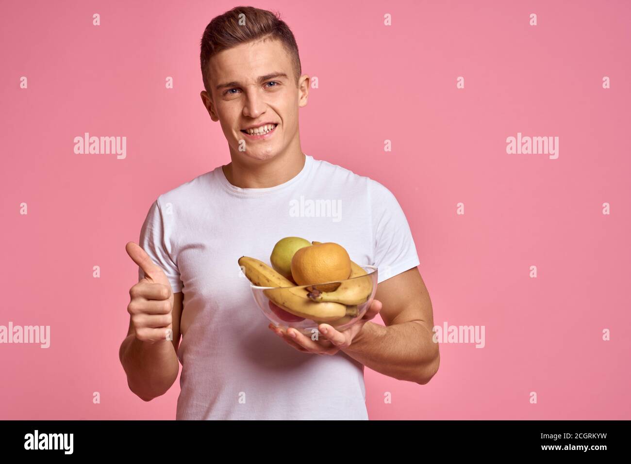 Man with fruits in hands on a pink background healthy food vitamins ...