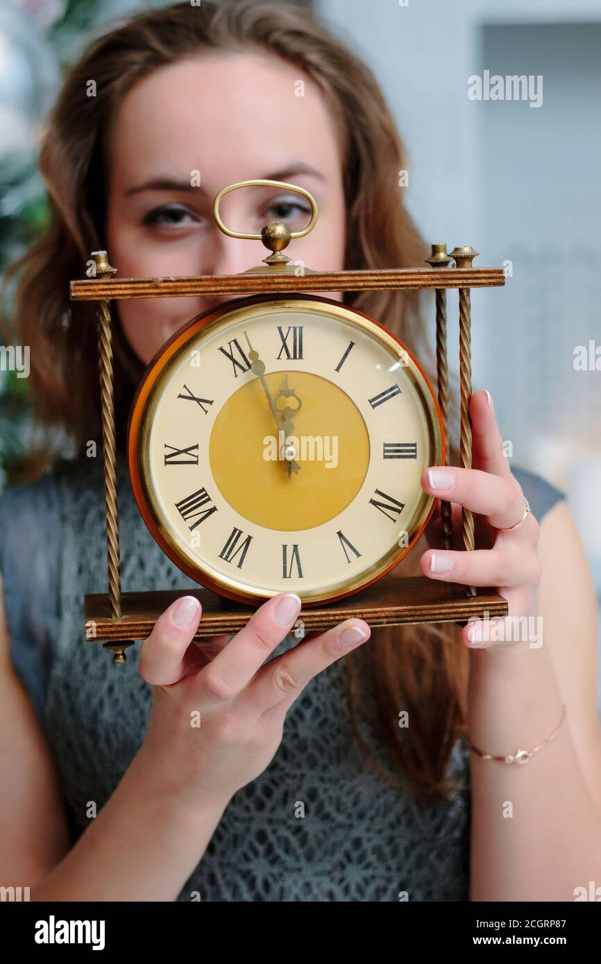 Young lady holding clocks behind face near christmas tree - christmas ...