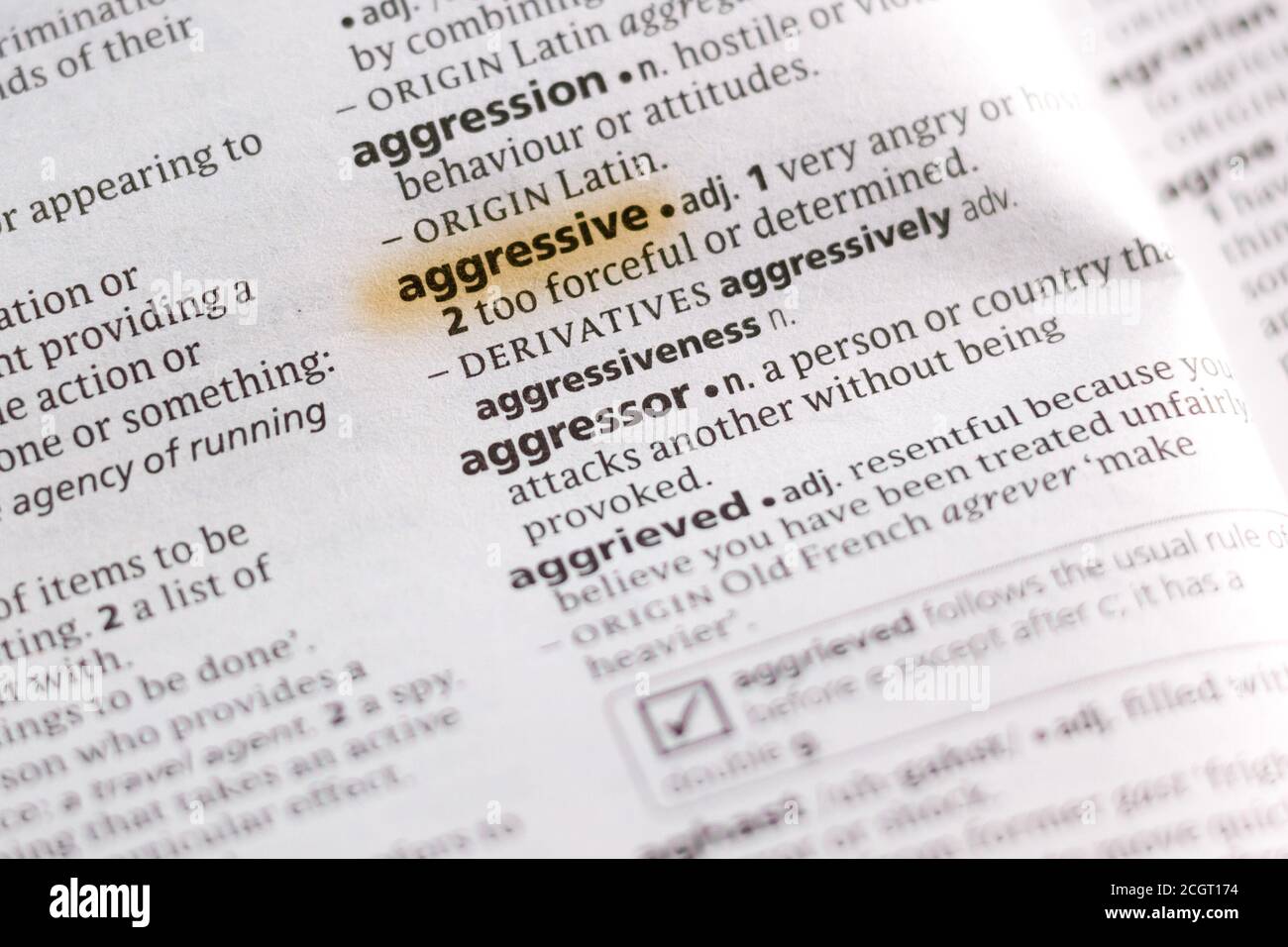The word or phrase Aggressive in a dictionary highlighted with marker ...