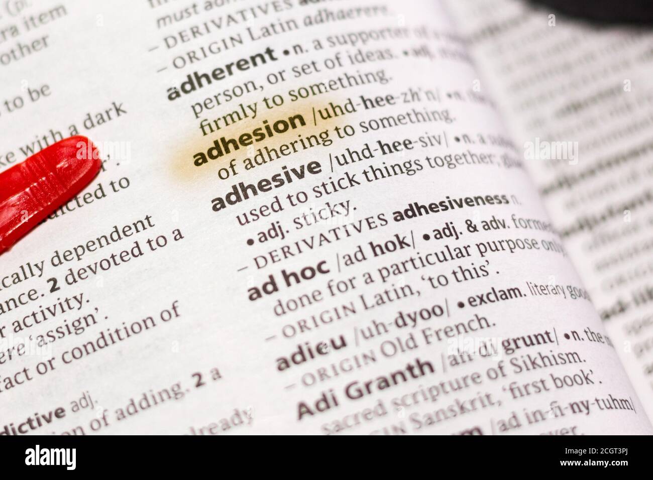 The word or phrase Adhesion in a dictionary highlighted with marker ...