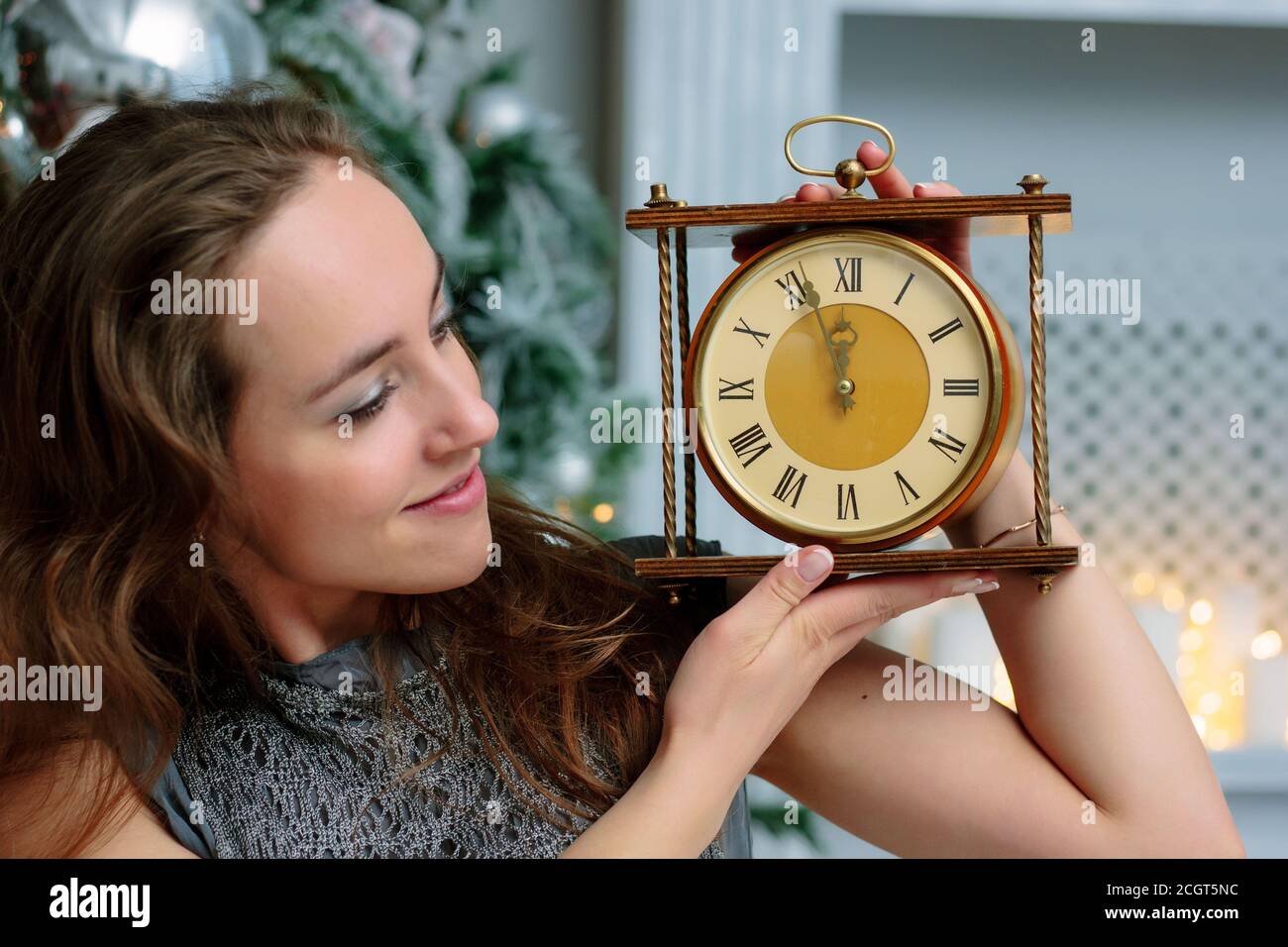 Beautiful girl holding clocks in hands in christmas room - christmas ...