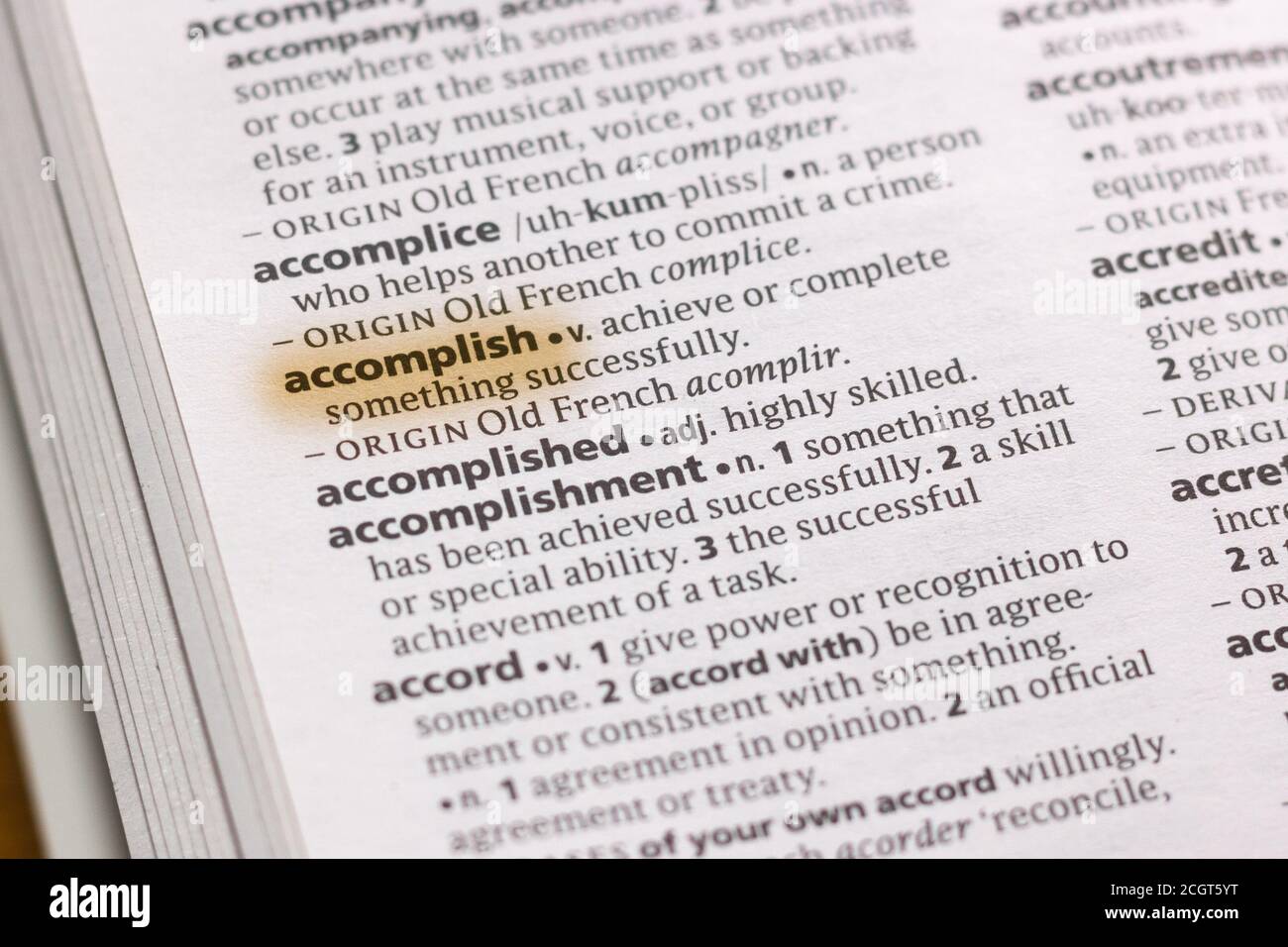 The word or phrase Accomplish in a dictionary highlighted with marker ...