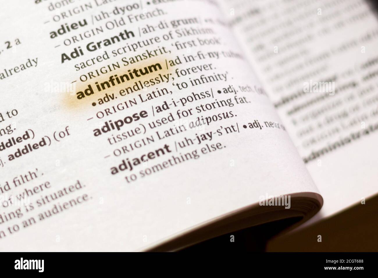 The word or phrase Ad Infinitum in a dictionary highlighted with marker ...