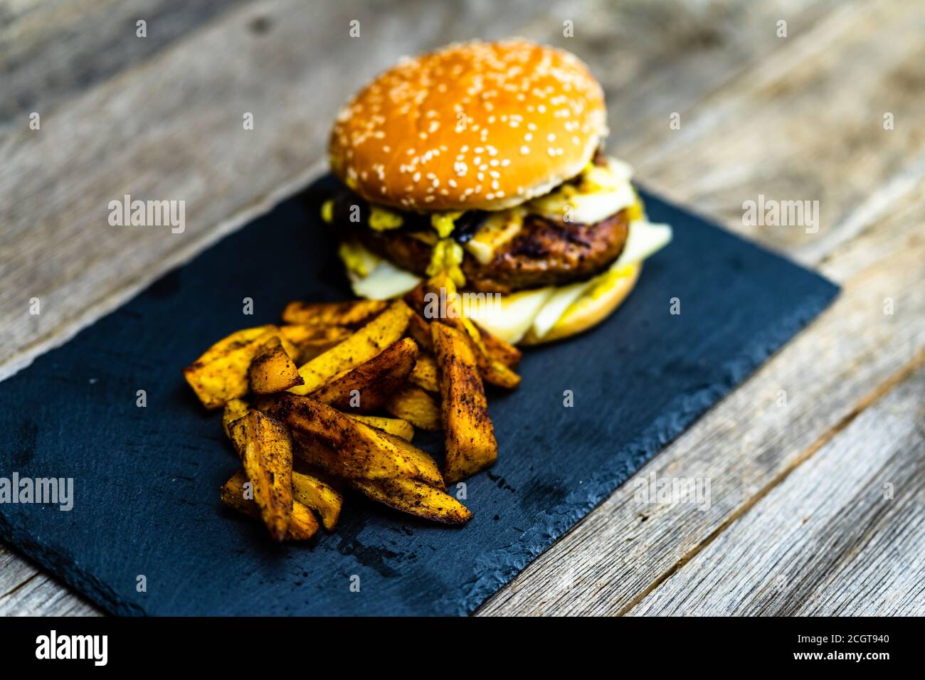 Homemade fresh tasty cheese burger and fried potatoes on a wooden table ...