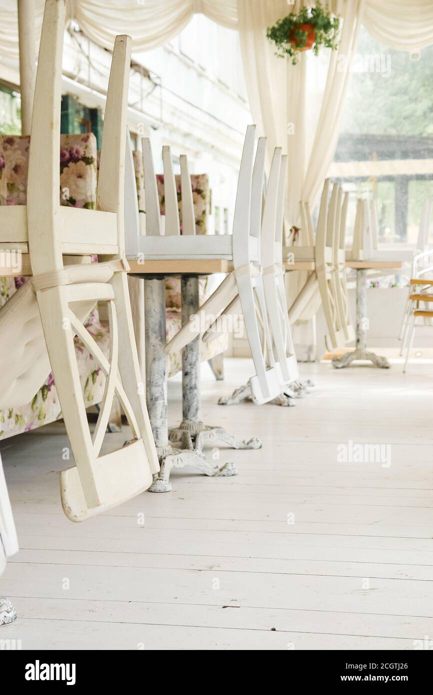 White chairs on tables upside down on street cafe summer terrace Stock ...
