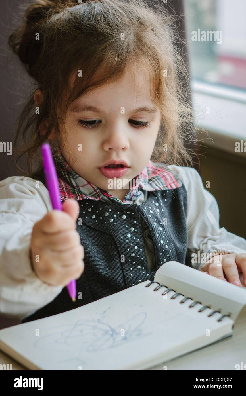 Little kid girl writing or drawing with pen in scetch book Stock Photo ...