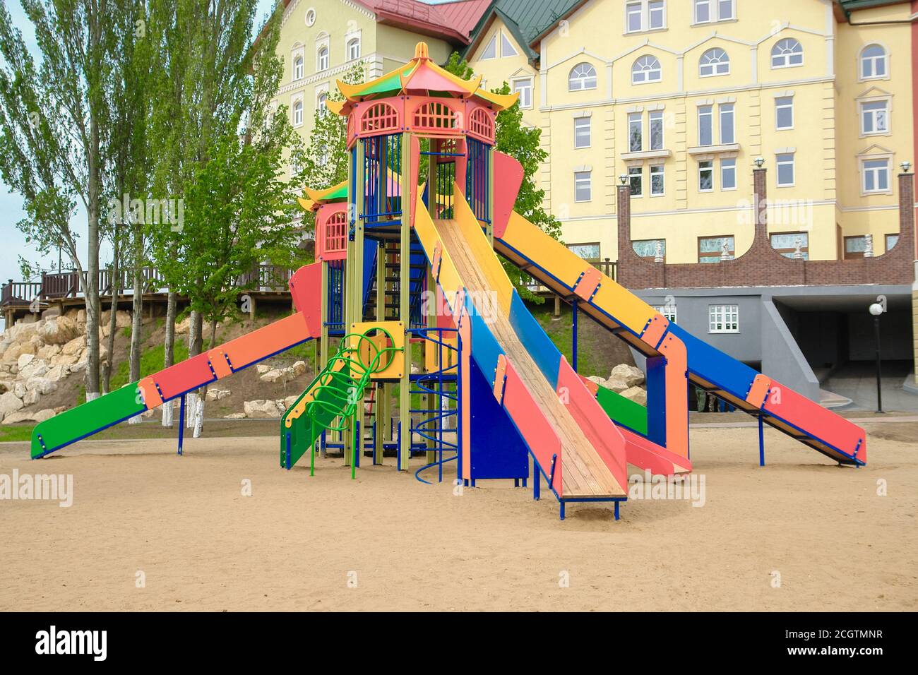 Colorful children playground on sand yard near beautiful buildings ...