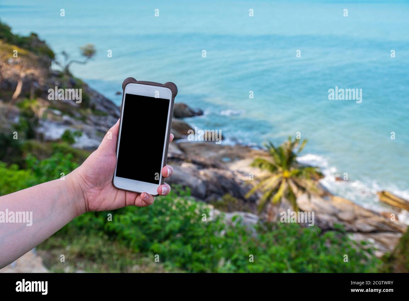 Hand young women using smart phone mobile relax on view of blue sea in ...