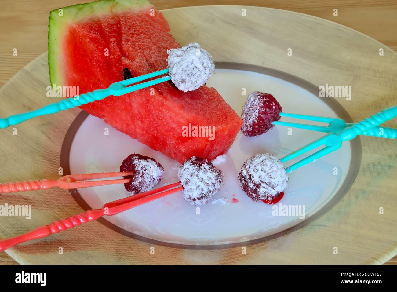 Raspberry in powdered sugar on skewers on a plate and watermelon Stock ...
