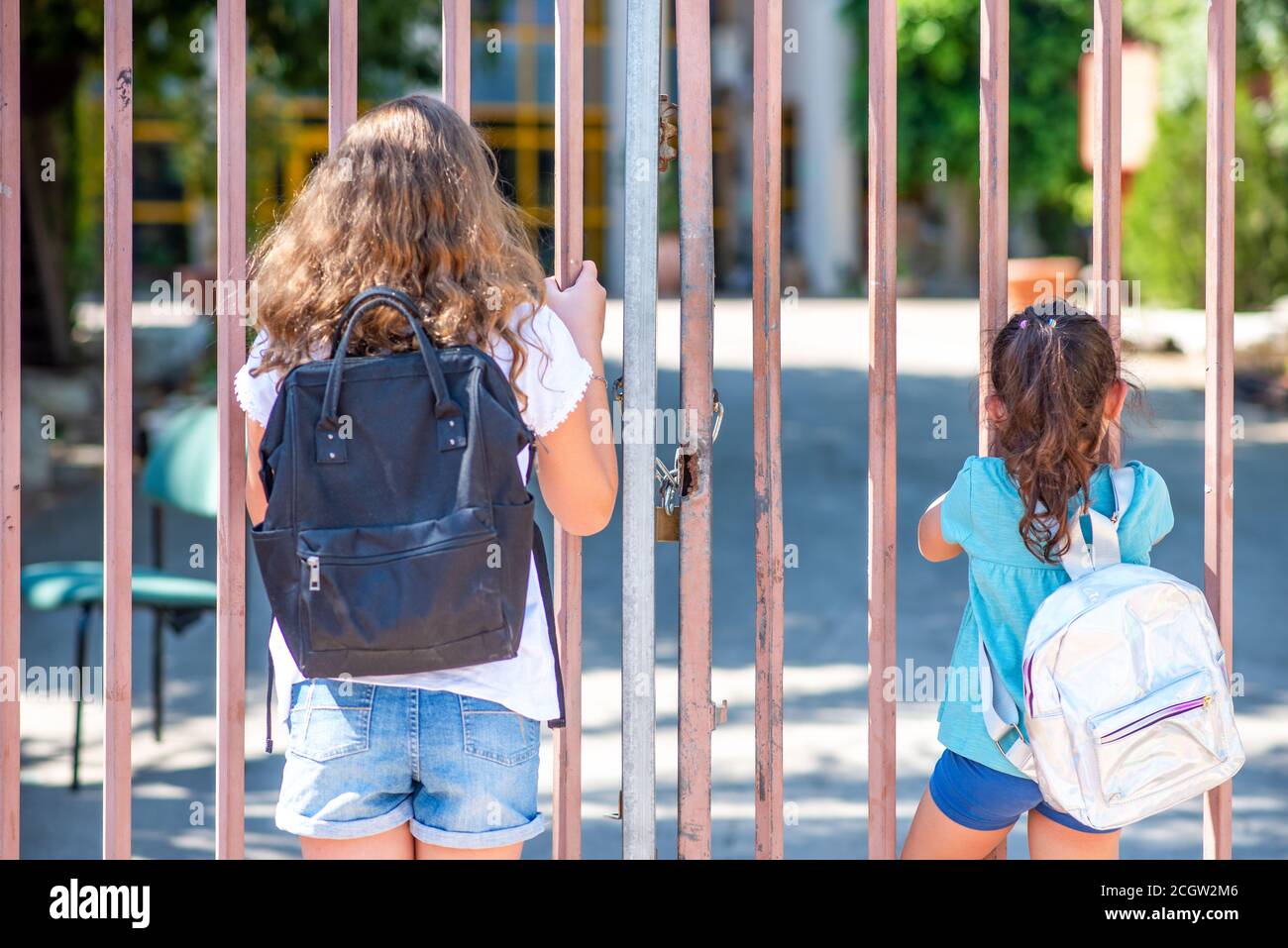 Children near gate of closed school. Little girls outside closed school ...