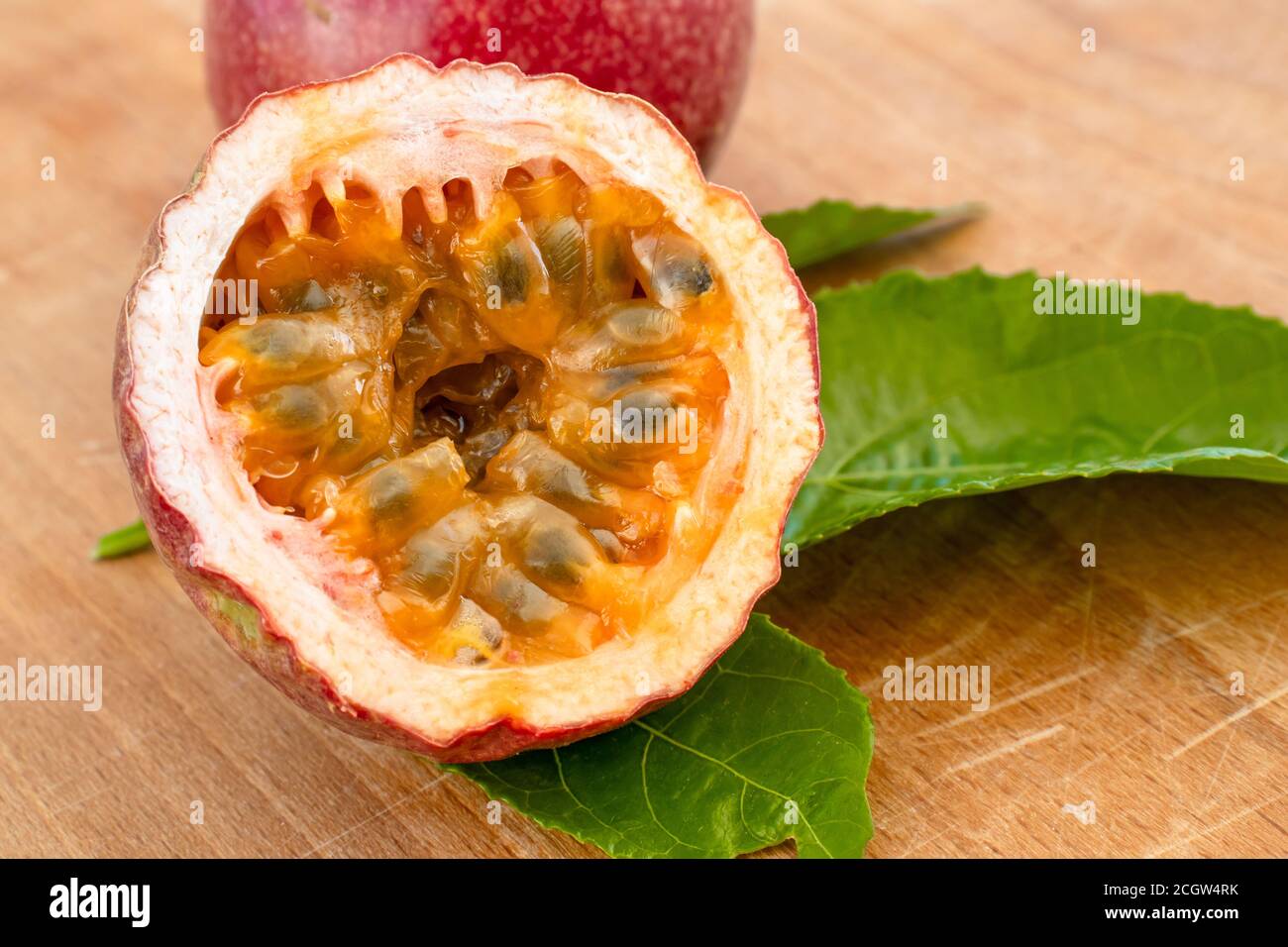 Maracuja cut in half and whole with leaf on wooden background. Passion ...