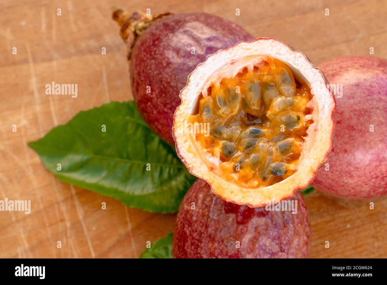 Maracuja cut in half and whole with leaf on wooden background. Passion ...