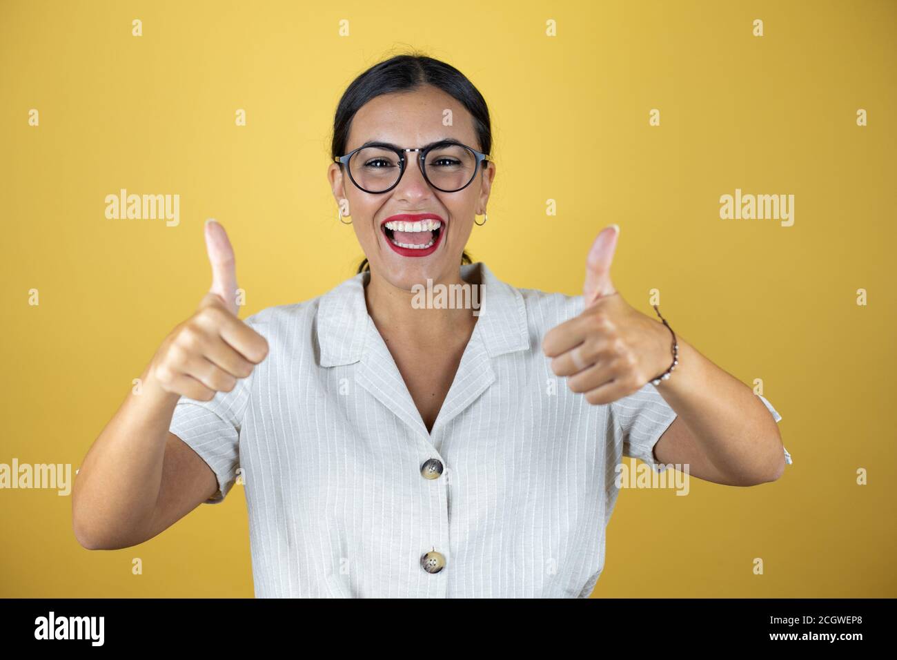 Beautiful woman over yellow background smiling and doing the okay ...